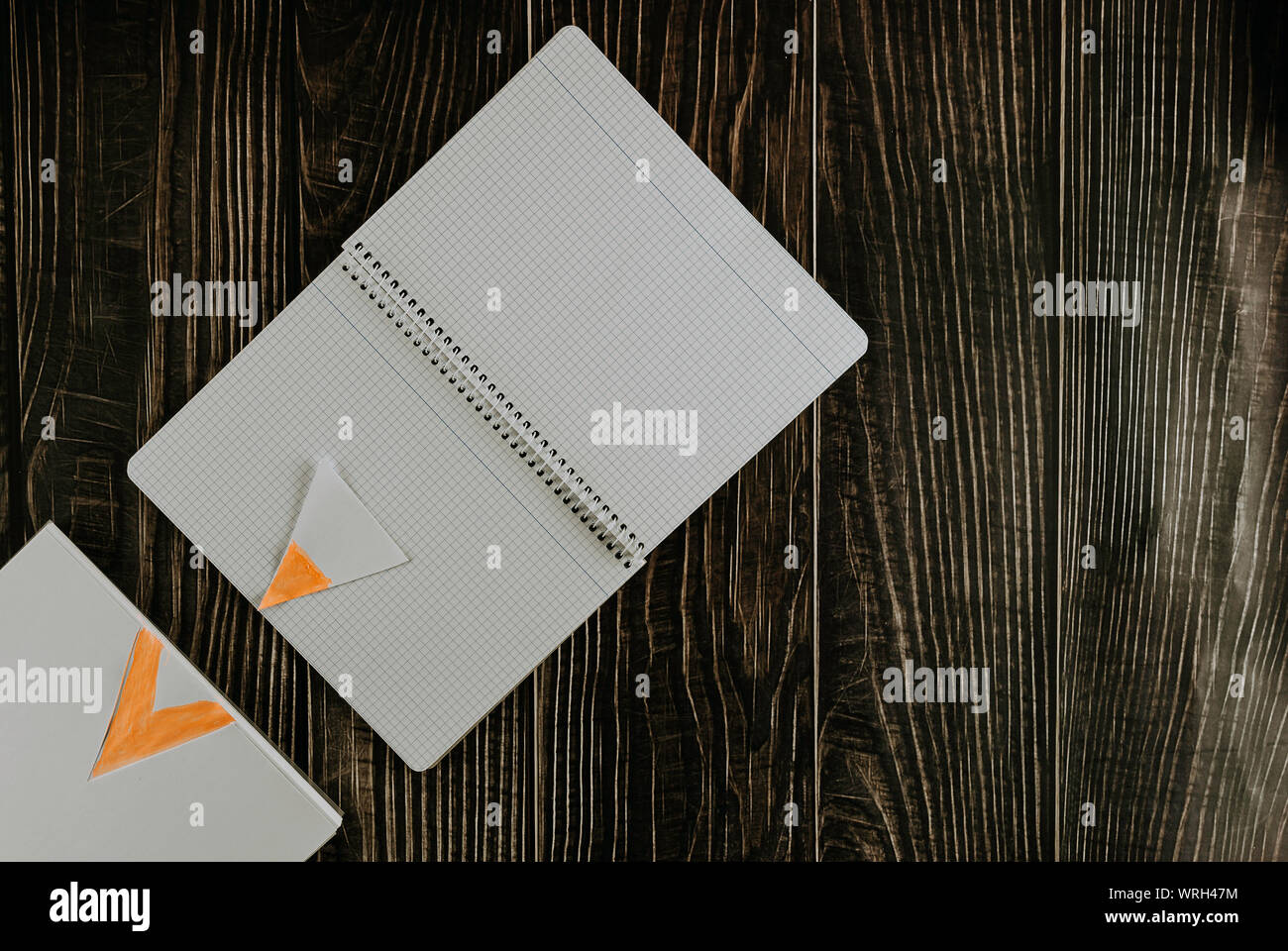 Grid notebook with cut orange triangle, concept work manuals, back to ...