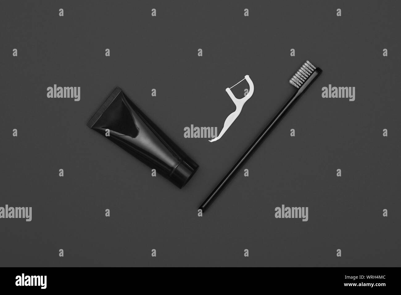 Close up one black toothpaste tube, floss and toothbrush over dark grey ...