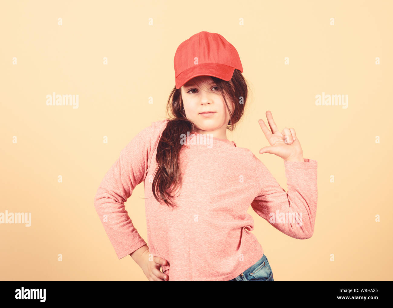 Cutie in cap. Girl cute child wear cap or snapback hat beige background ...