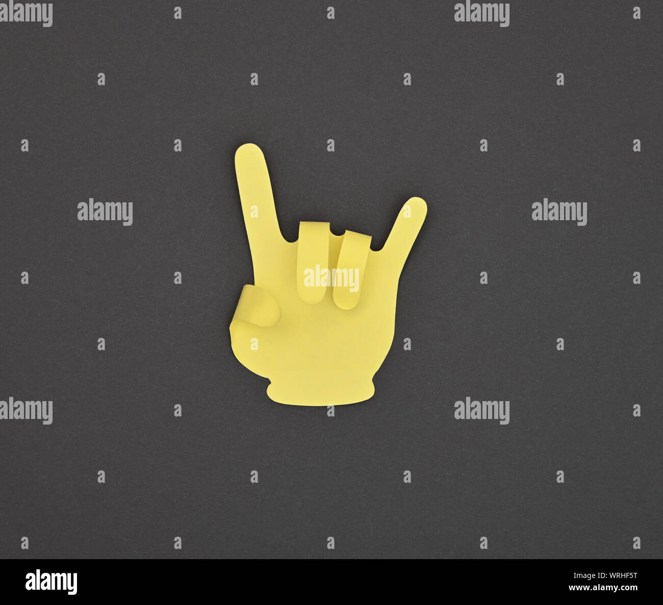 Paper made yellow DEVIL HORNS hand gesture sticker over grey background ...