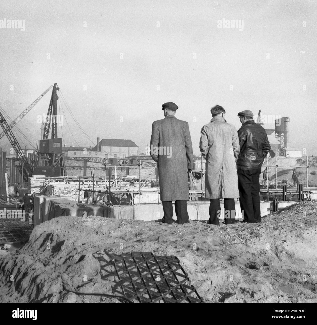 1950s, histrical, three men looking over a building site, the ...