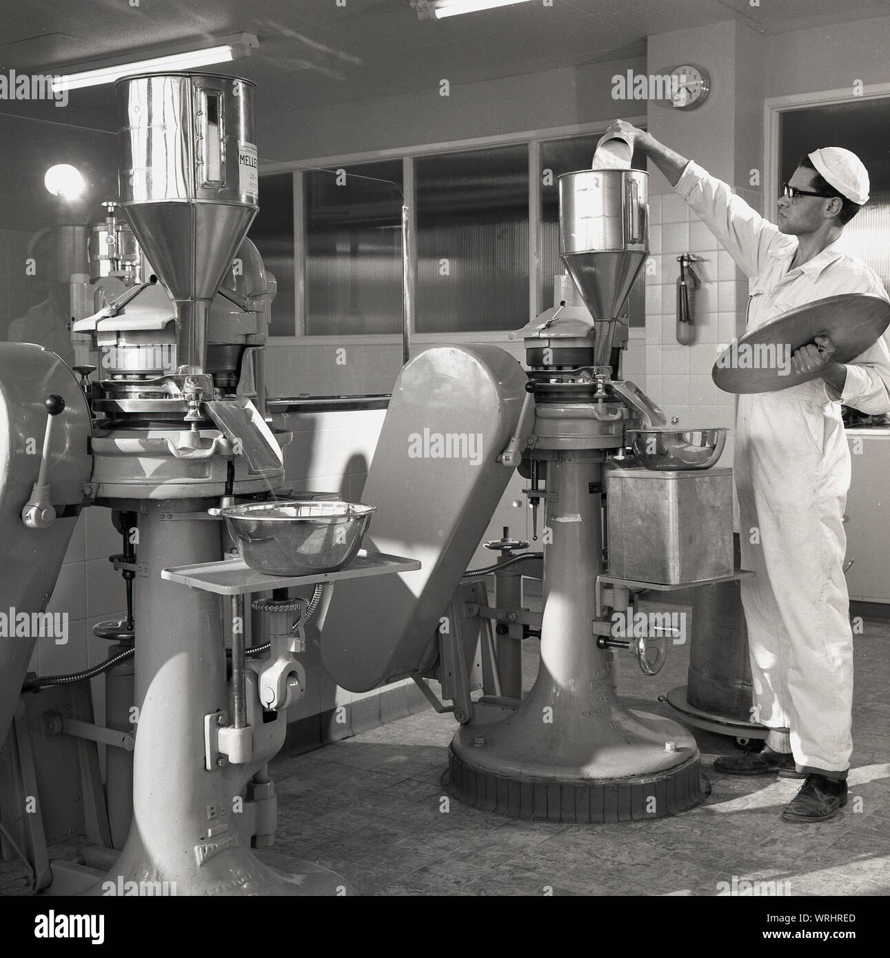 1950s, historical, a male worker in a white-coat pouring medical powder ...