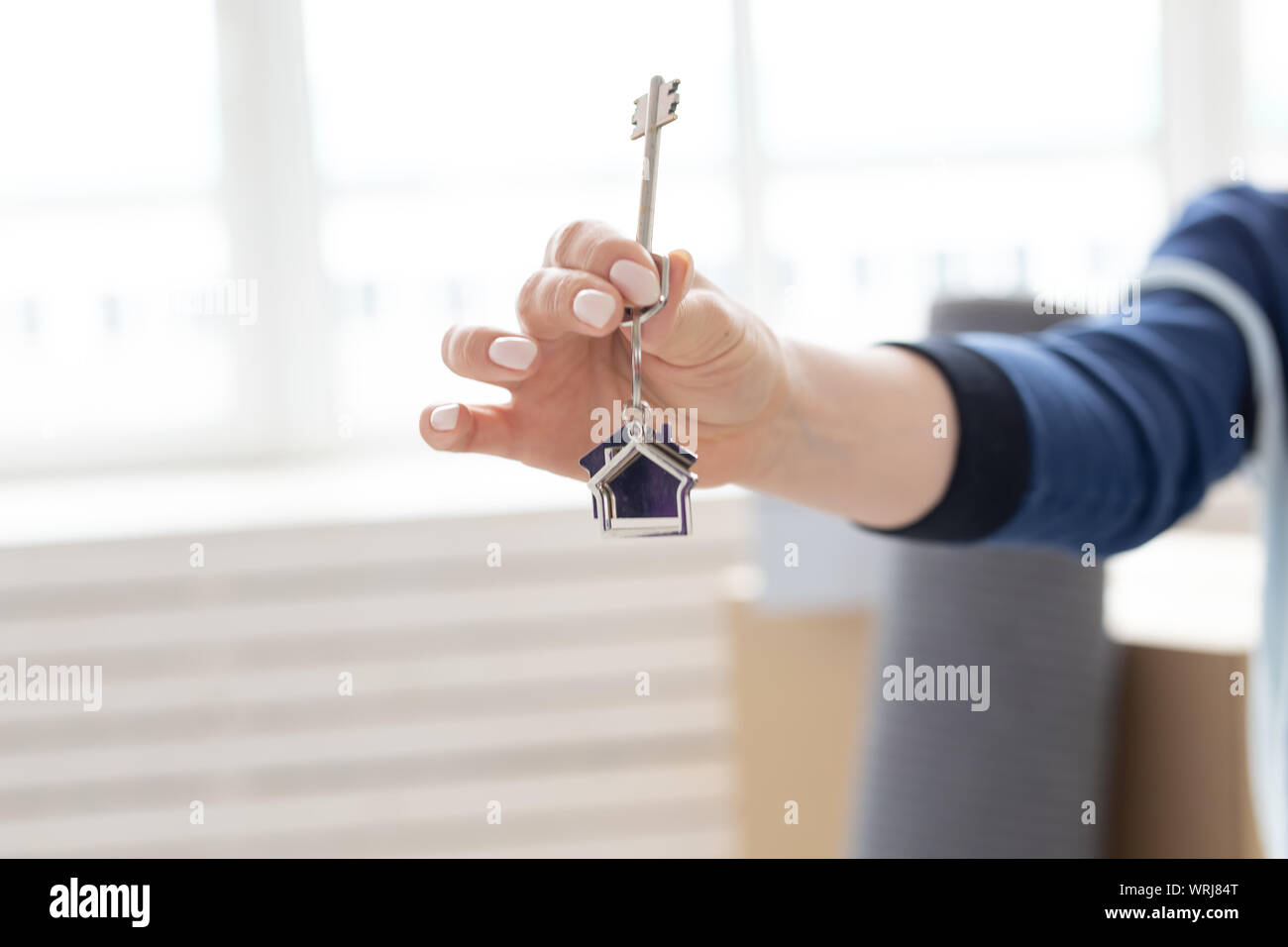 Real estate, moving and renting concept - Female hand holding keys with ...