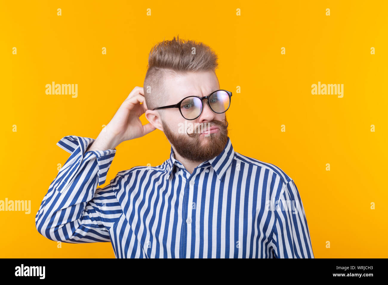 Cute intelligent young man with a beard and with glasses poses on a ...