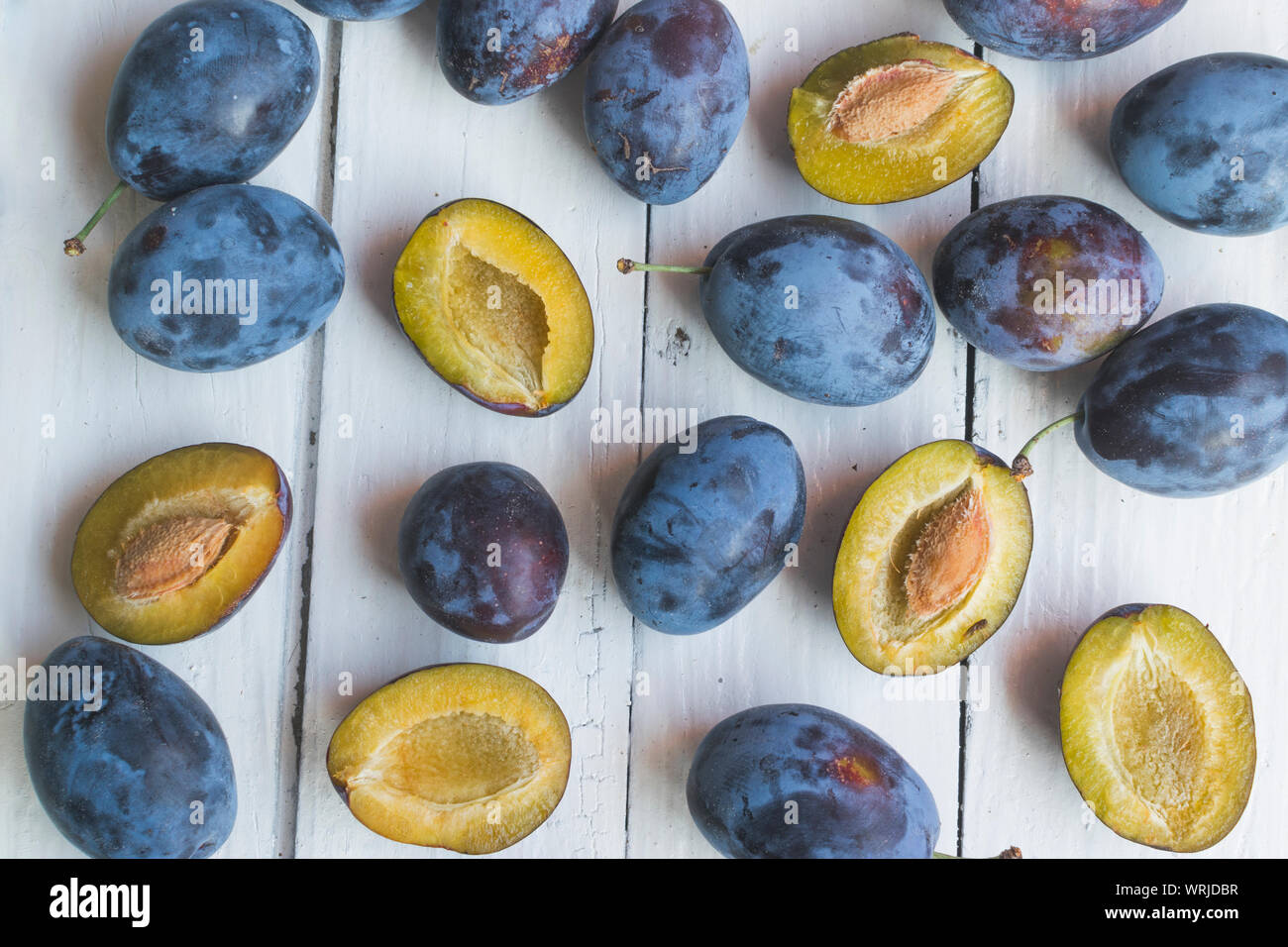 Fresh and ripped delicious plums on old white wooden table. High angle ...
