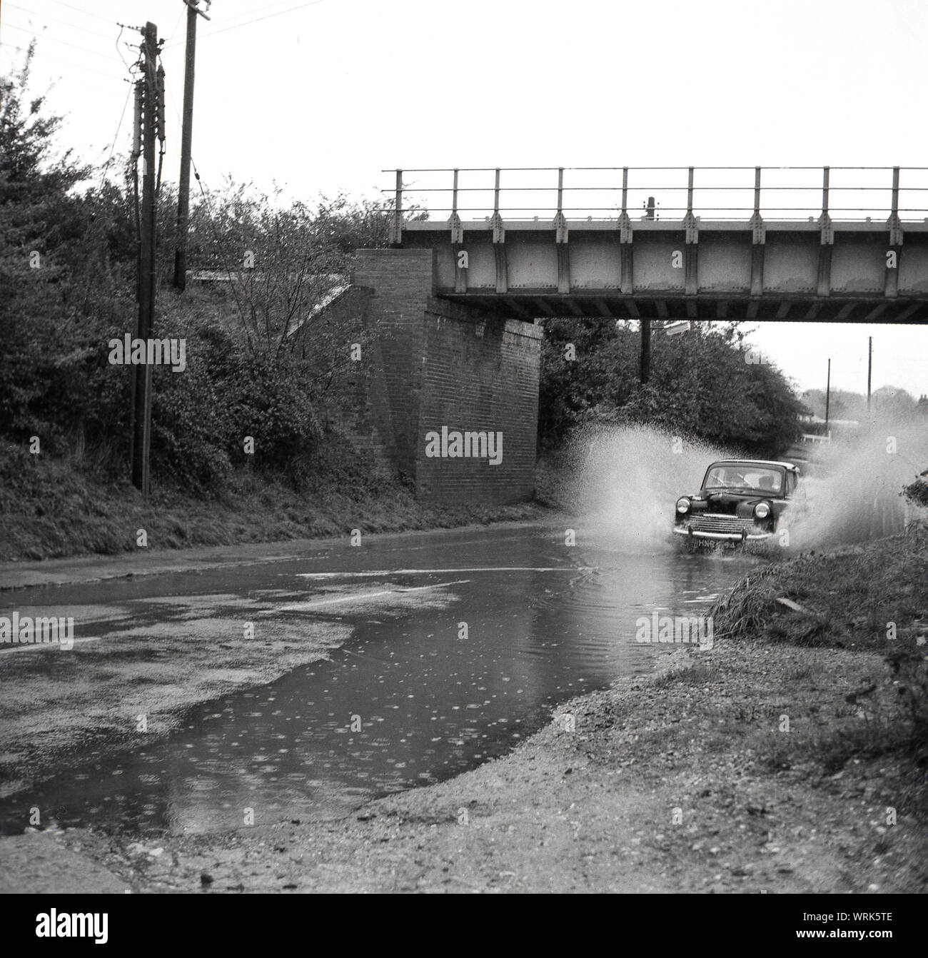 1967, historical, flooded road, car of the era going under a bridge ...
