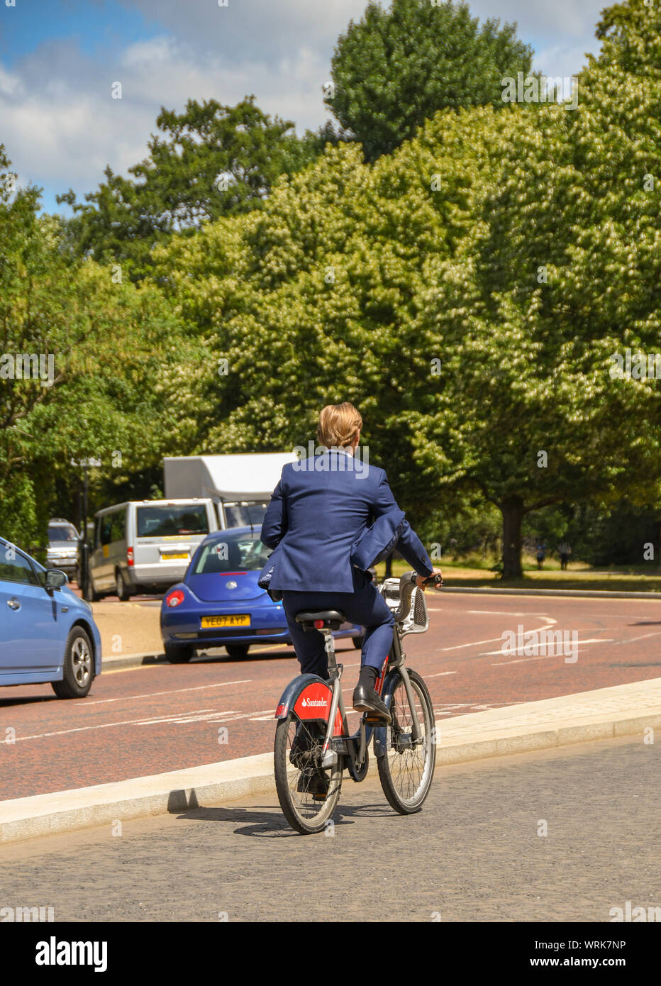 LONDON, ENGLAND - JULY 2018: Person in a suit riding a bike from one of ...