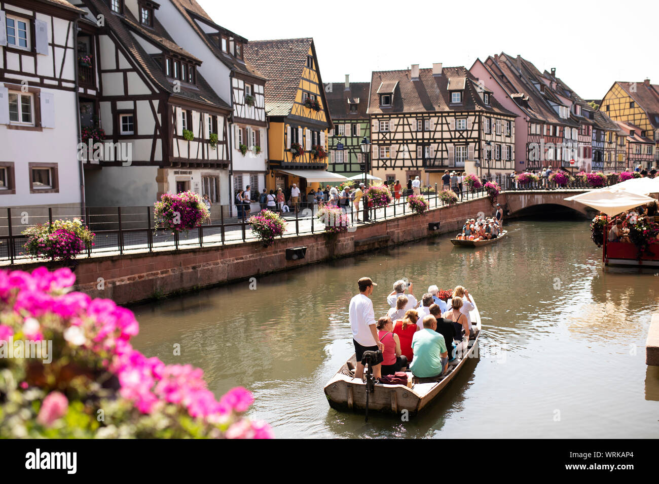 A flat-bottomed boat takes tourists down the canal past the half ...
