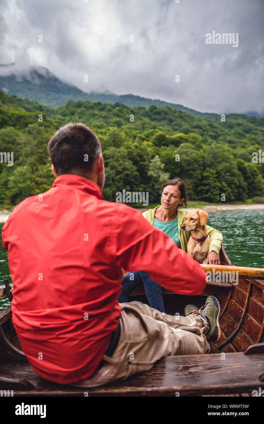Couple with a small yellow dog rowing a boat on a mountain lake Stock ...