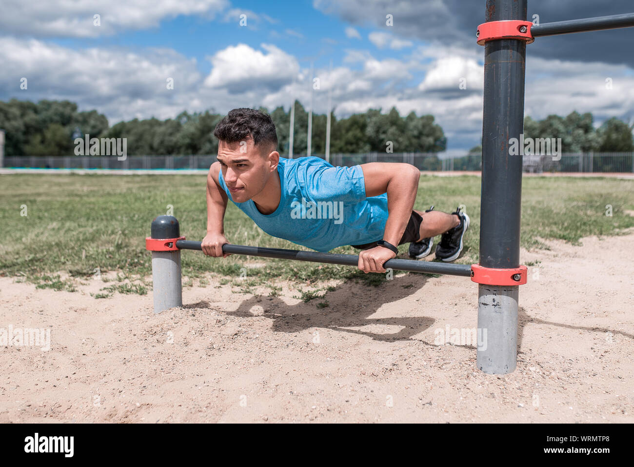Male athlete does push-ups, fitness workout training, from crossbar in ...