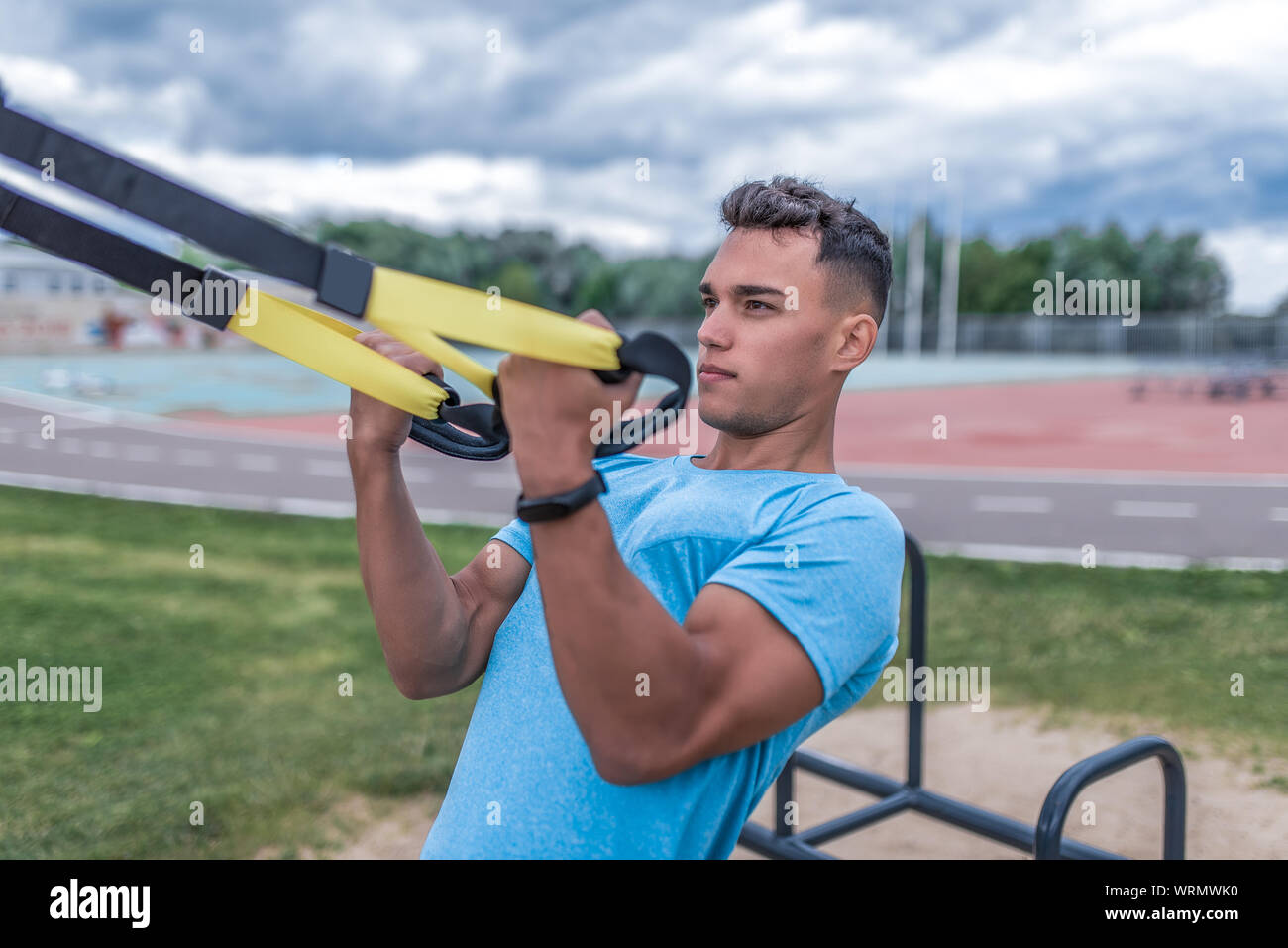 Male athlete training hands lifting on biceps hinges, active straps ...