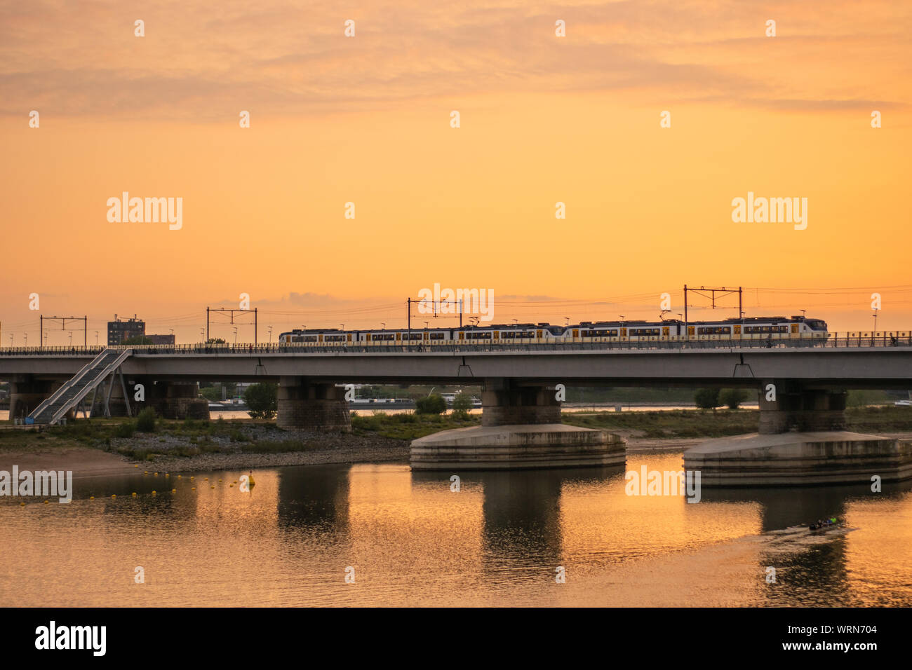 Dutch train crossing a bridge over the river waal during sunset Stock ...