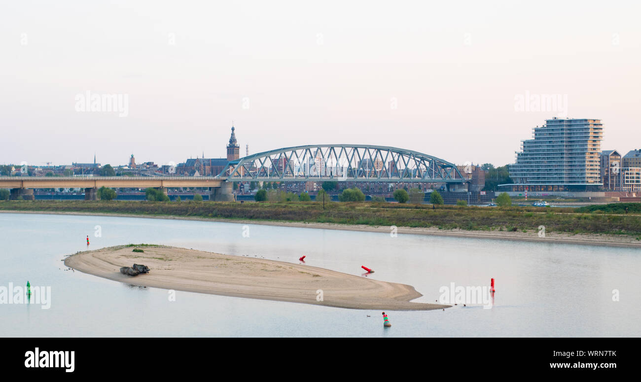 an island in the river Waal with the skyline of the Dutch city Nijmegen ...