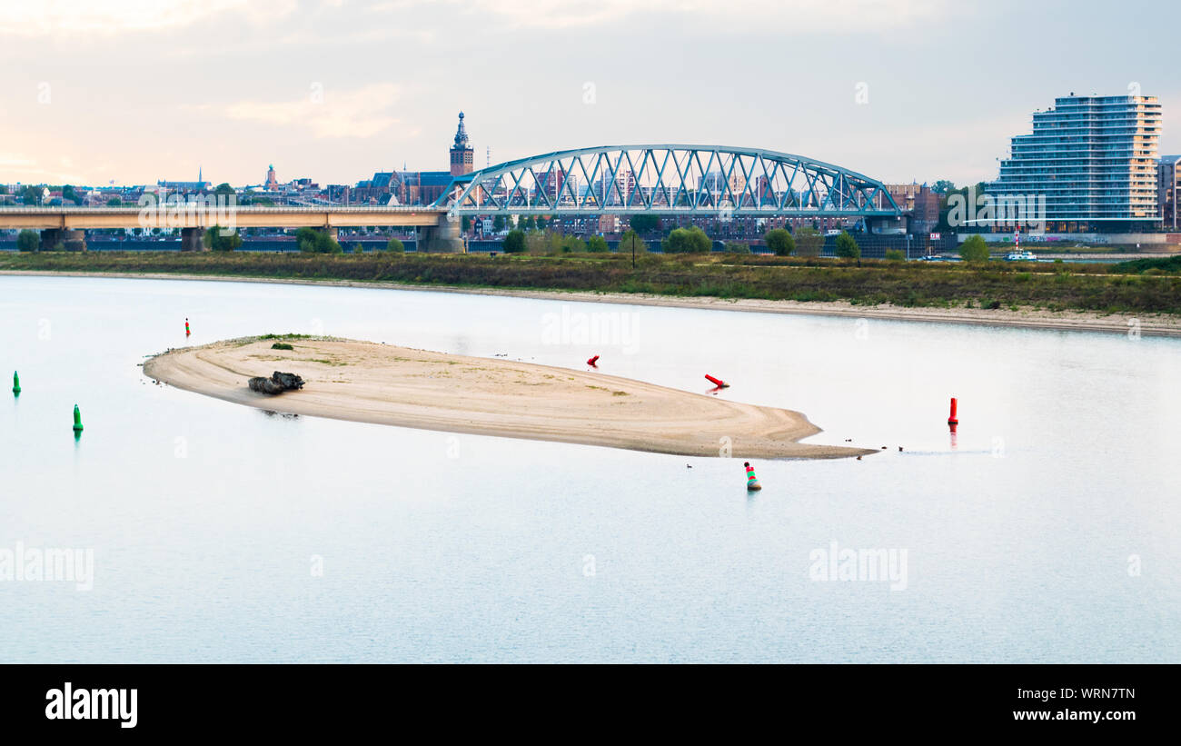 an island in the river Waal with the skyline of the Dutch city Nijmegen ...