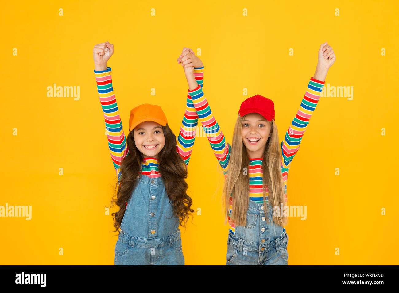 Celebrating victory. Happy girls celebrating achievement on yellow ...
