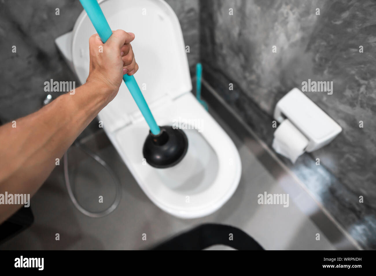 Toilet repair by hand with a Toilet Plunger. Plumbing. A plumber uses a ...