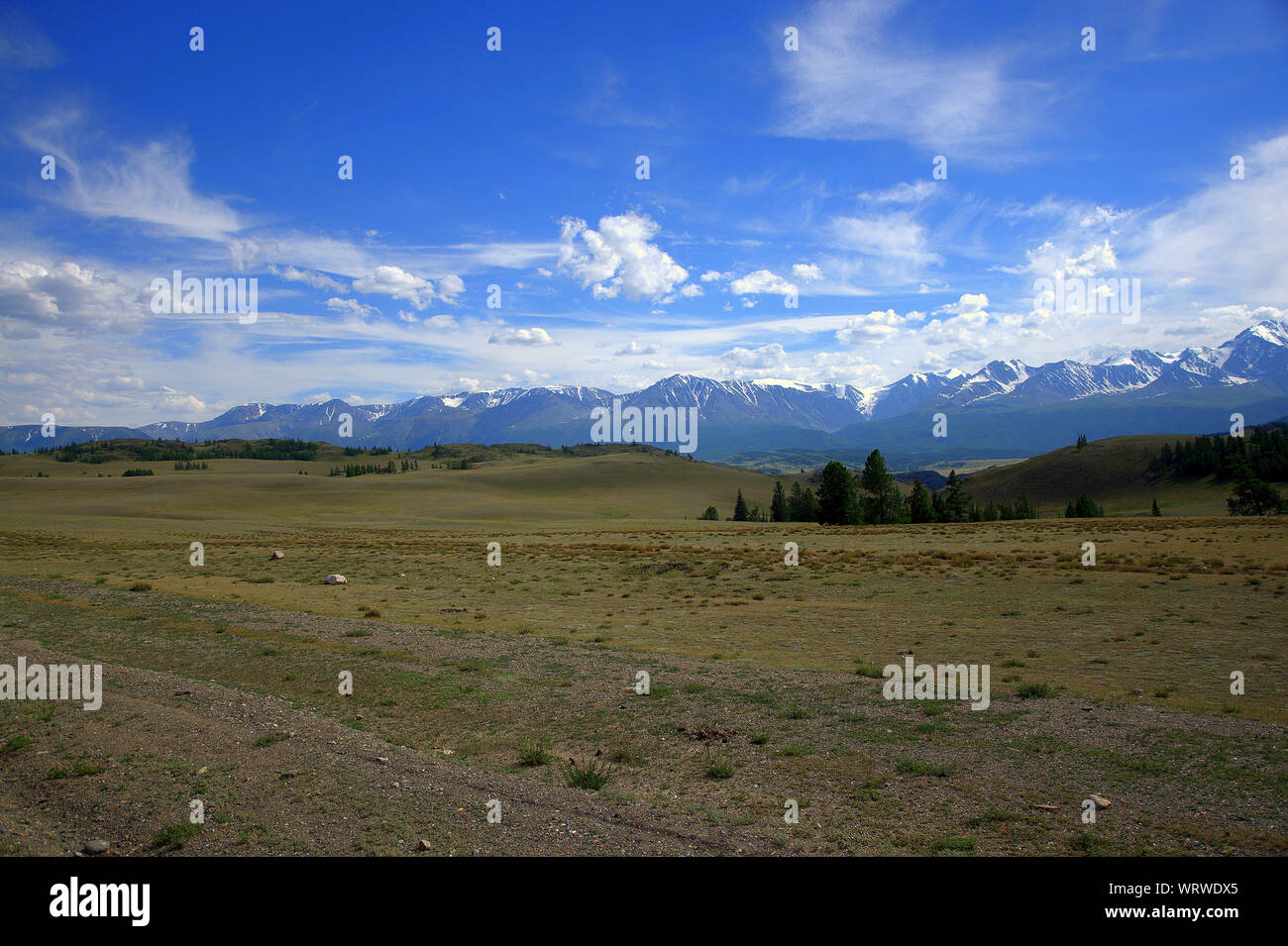 Steppe landscape at the foot of the mountain ranges covered with snow ...