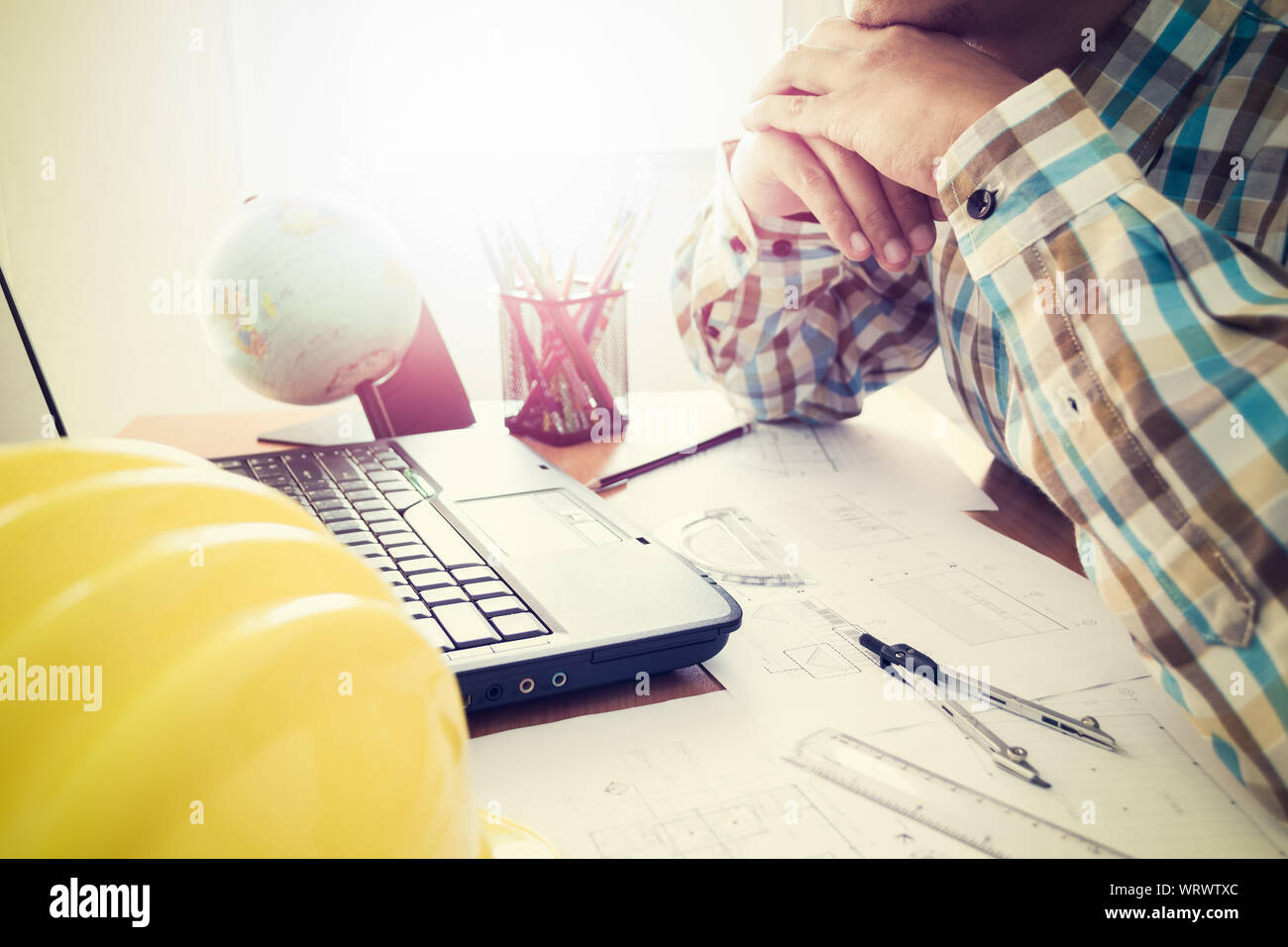Architect with construction plan on office desk under shinning light ...