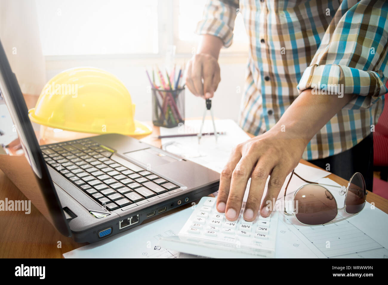 Architect working on calculator dividers with construction plan in ...