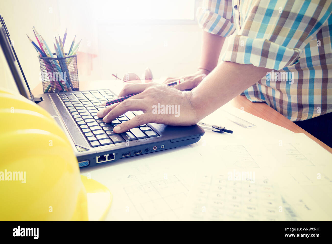 Architect working on laptop with construction plan in office Stock ...