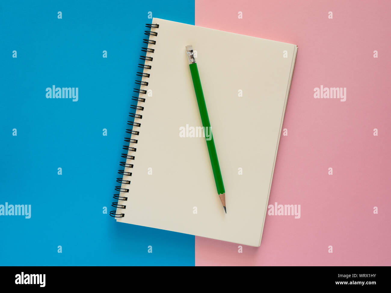 Open notebook with green pencil isolated on pink and blue paper ...