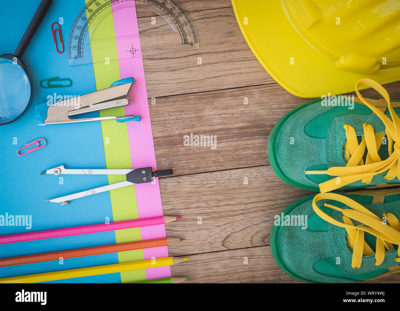 Sneakers, construction helmet, writing material and other on wooden ...