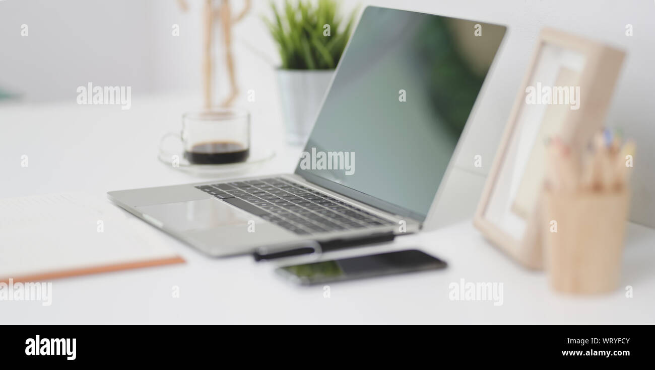 Open laptop computer with office supplies and decorations on white ...