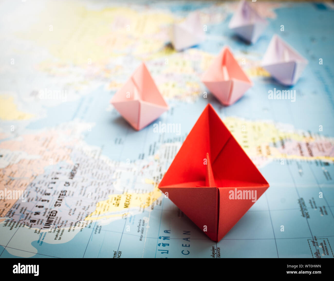 Paper boats following a red leader boat on world map. Concept for ...