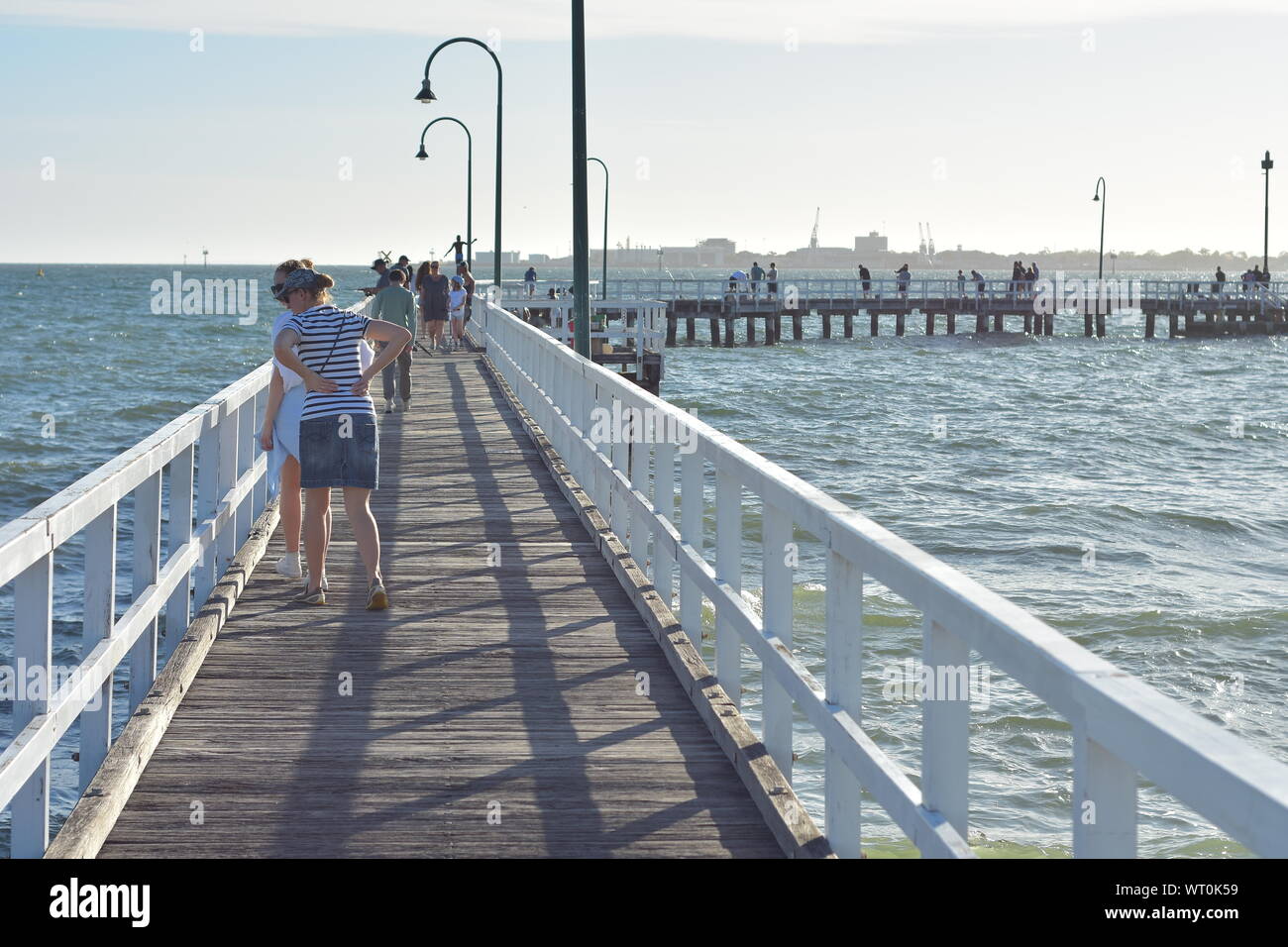 People walking and resting on retired industrial wharf with wooden ...