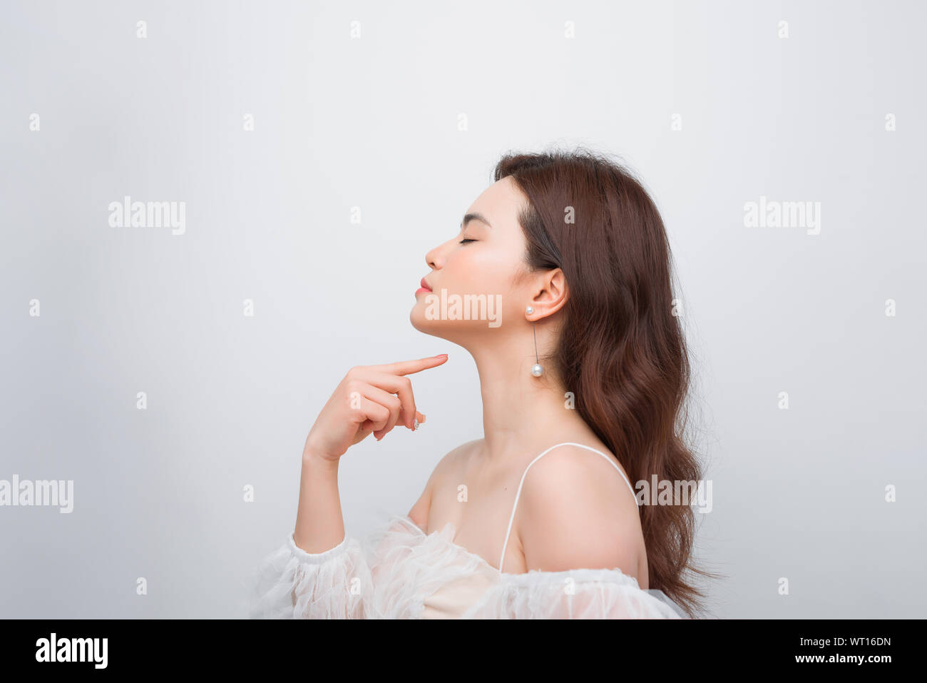 Young beautiful Asian woman pointing at neck in white isolated ...