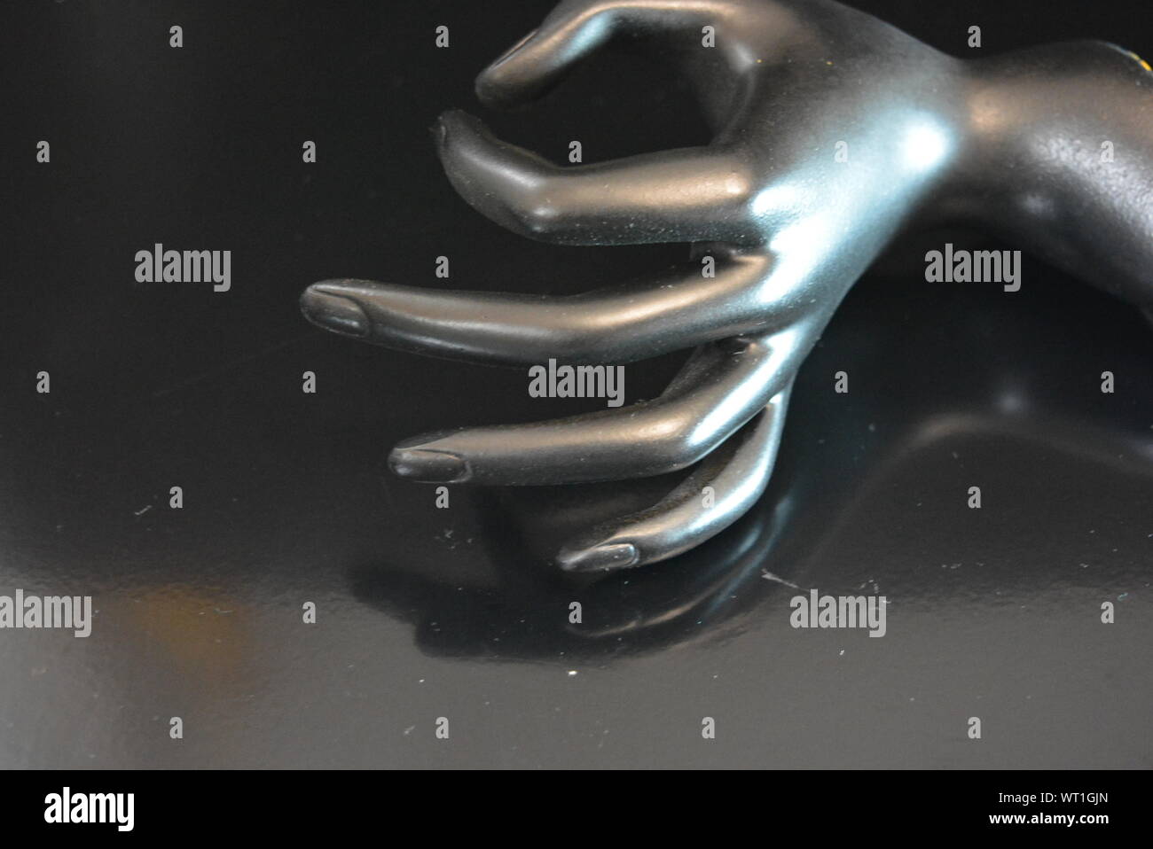 A matte black ceramic hand-shaped statuette is located on a matte black ...