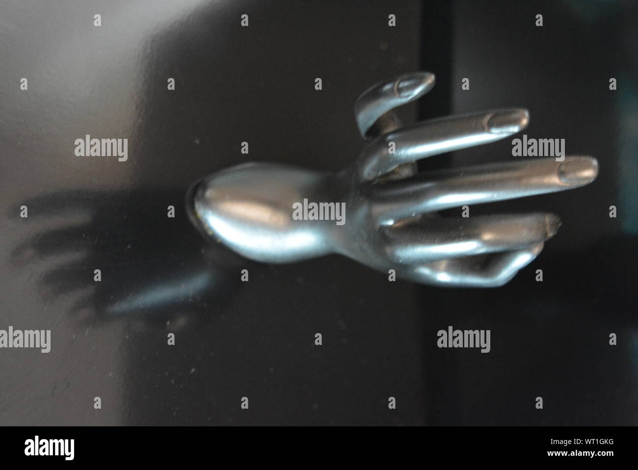 A matte black ceramic hand-shaped statuette is located on a matte black ...