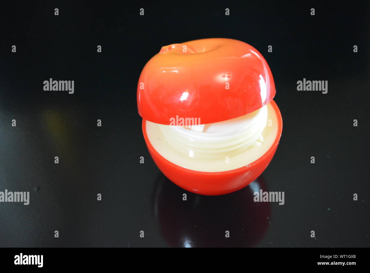 A bright red yellow plastic apple in which a cream of skin and face ...
