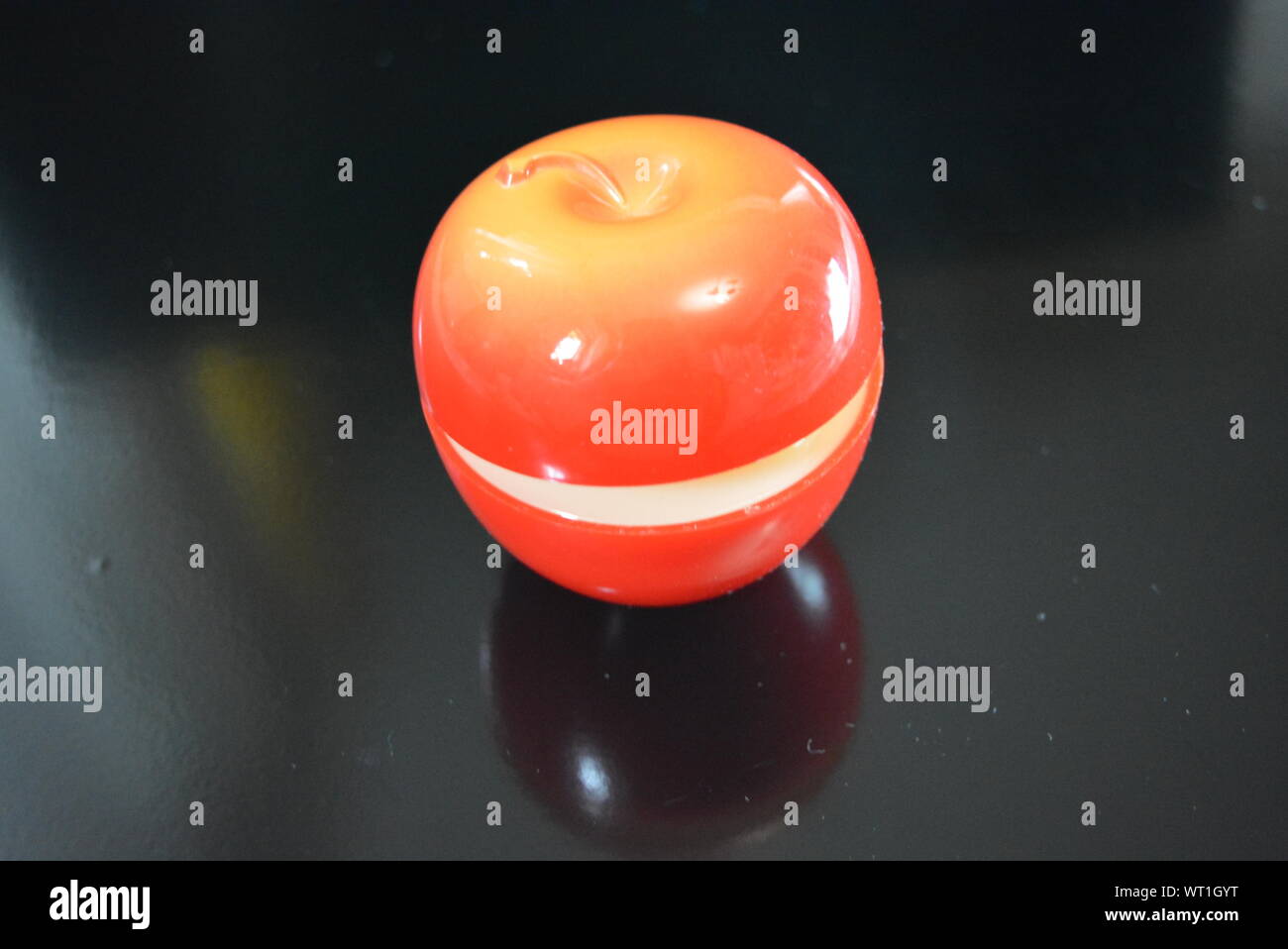 A bright red yellow plastic apple in which a cream of skin and face ...