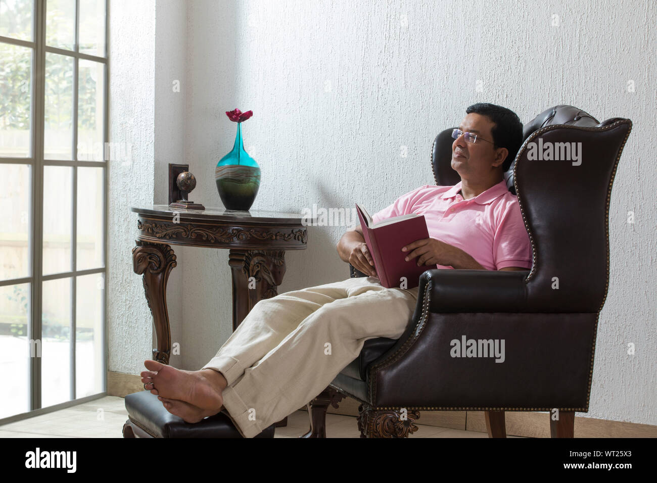 man sitting on a chair and reading a book Stock Photo - Alamy