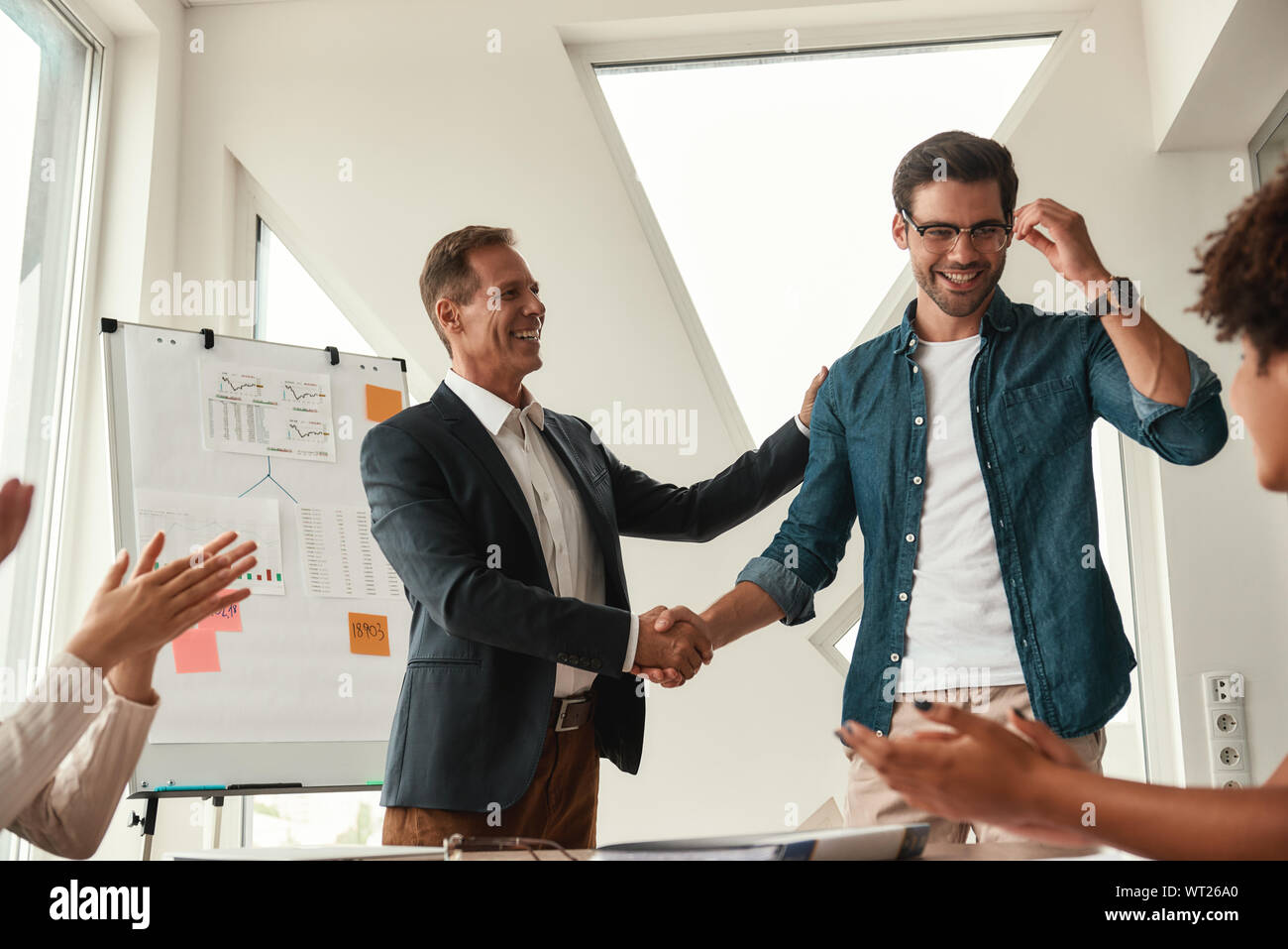 Welcome to our team Two cheerful colleagues shaking hands and smiling ...