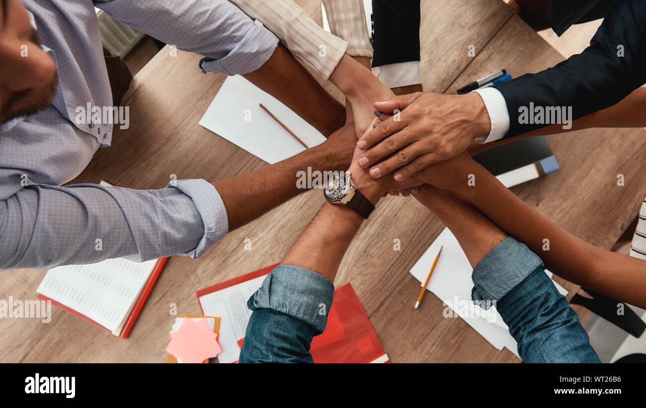 Strong team. Top view of business people holding hands together while ...