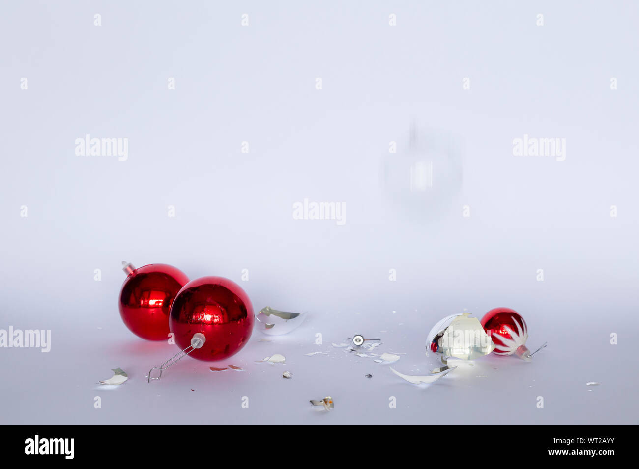 Falling and broken red and silver Christmas baubles on white background ...