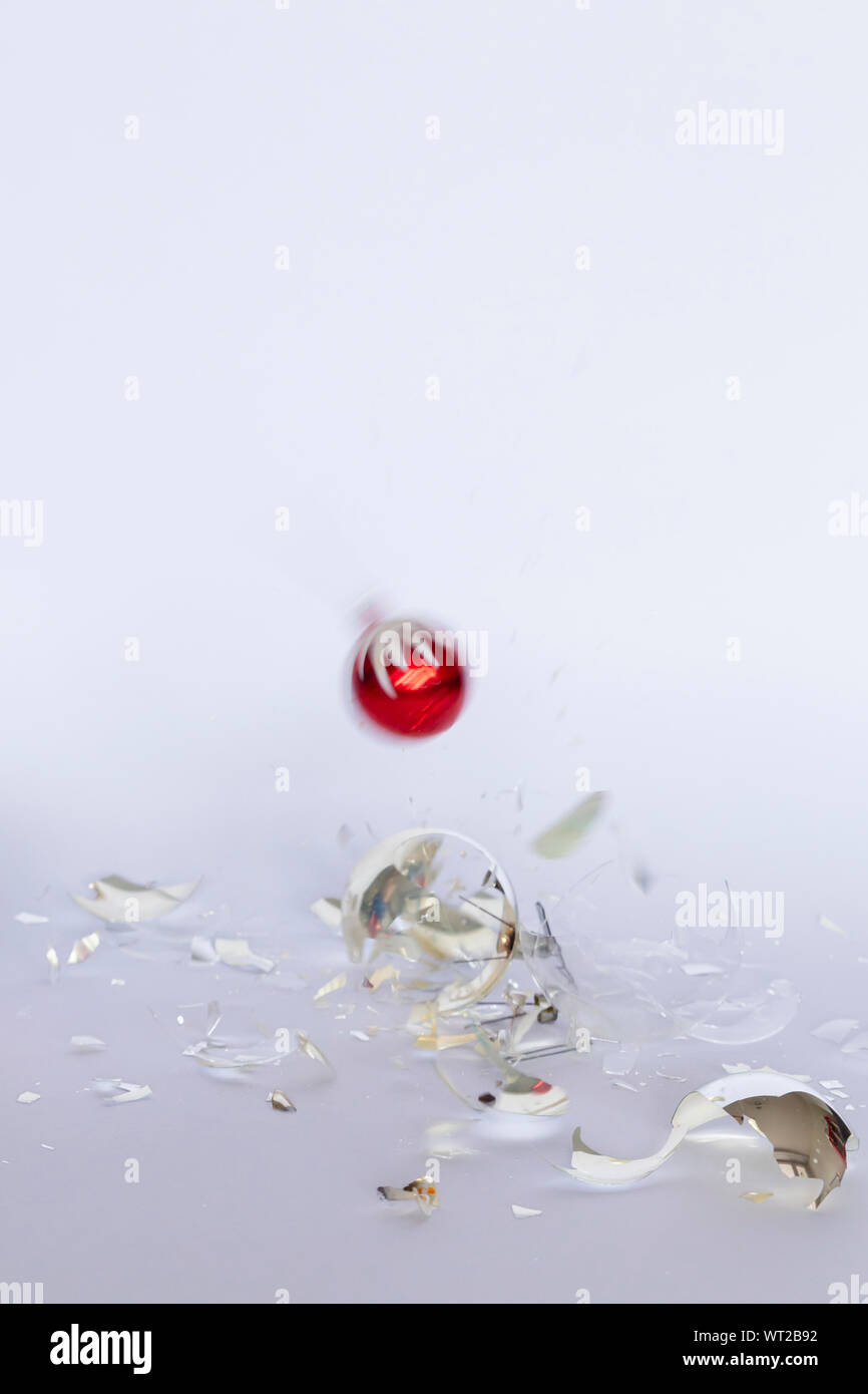 Falling and broken red and silver Christmas baubles on white background ...