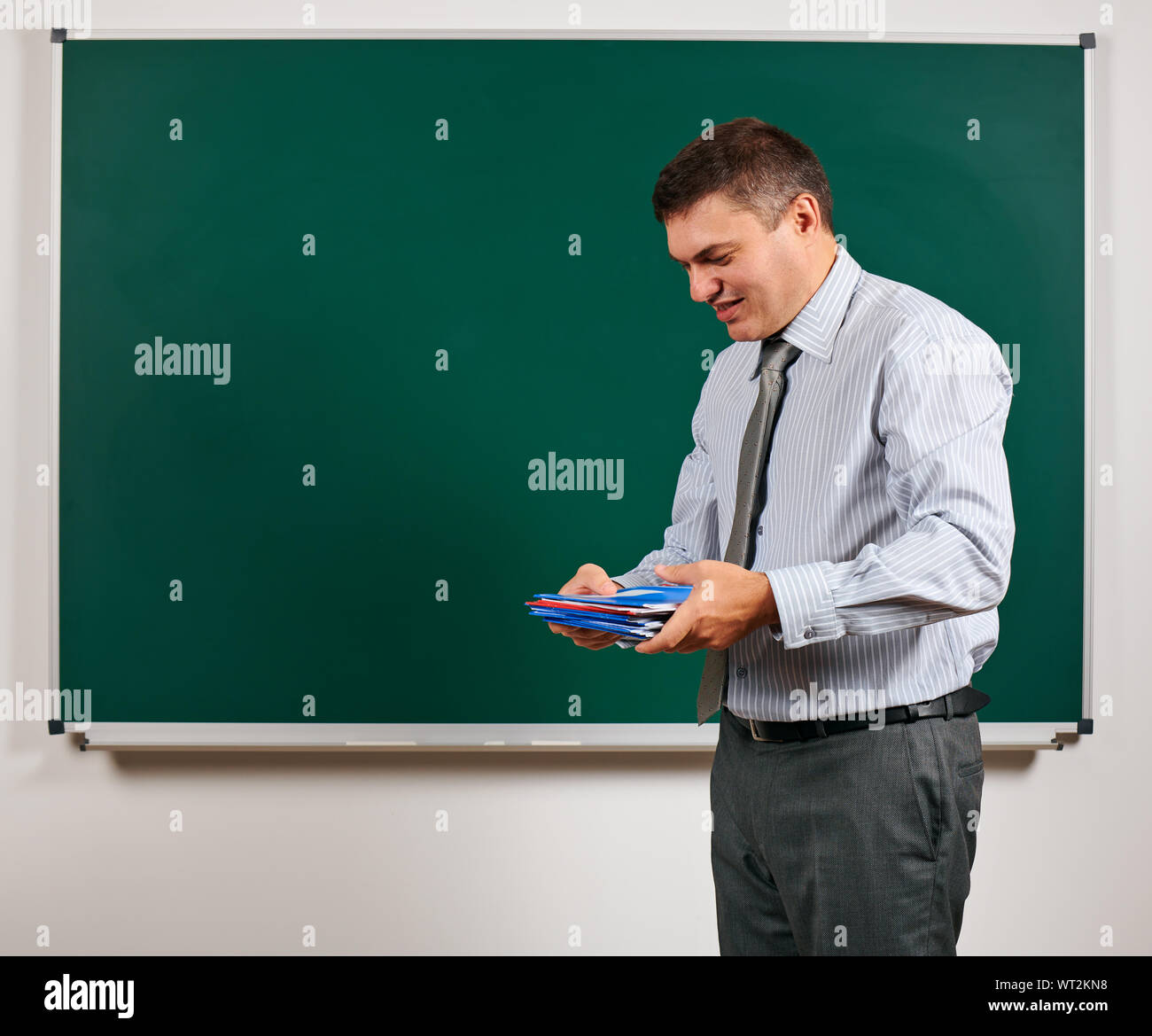 Portrait of a man as a teacher, posing at school board background ...