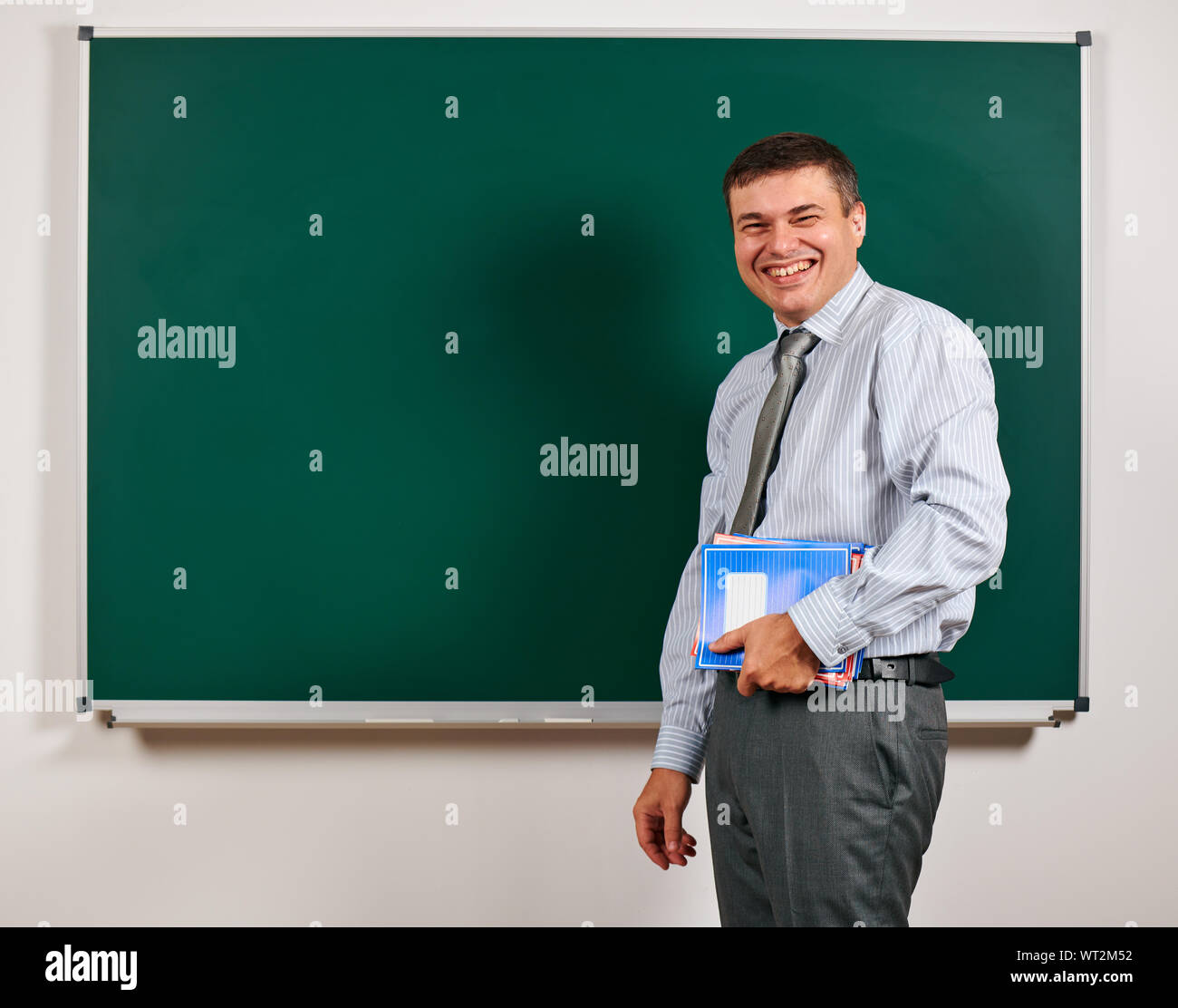 Portrait of a man as a teacher, posing at school board background ...