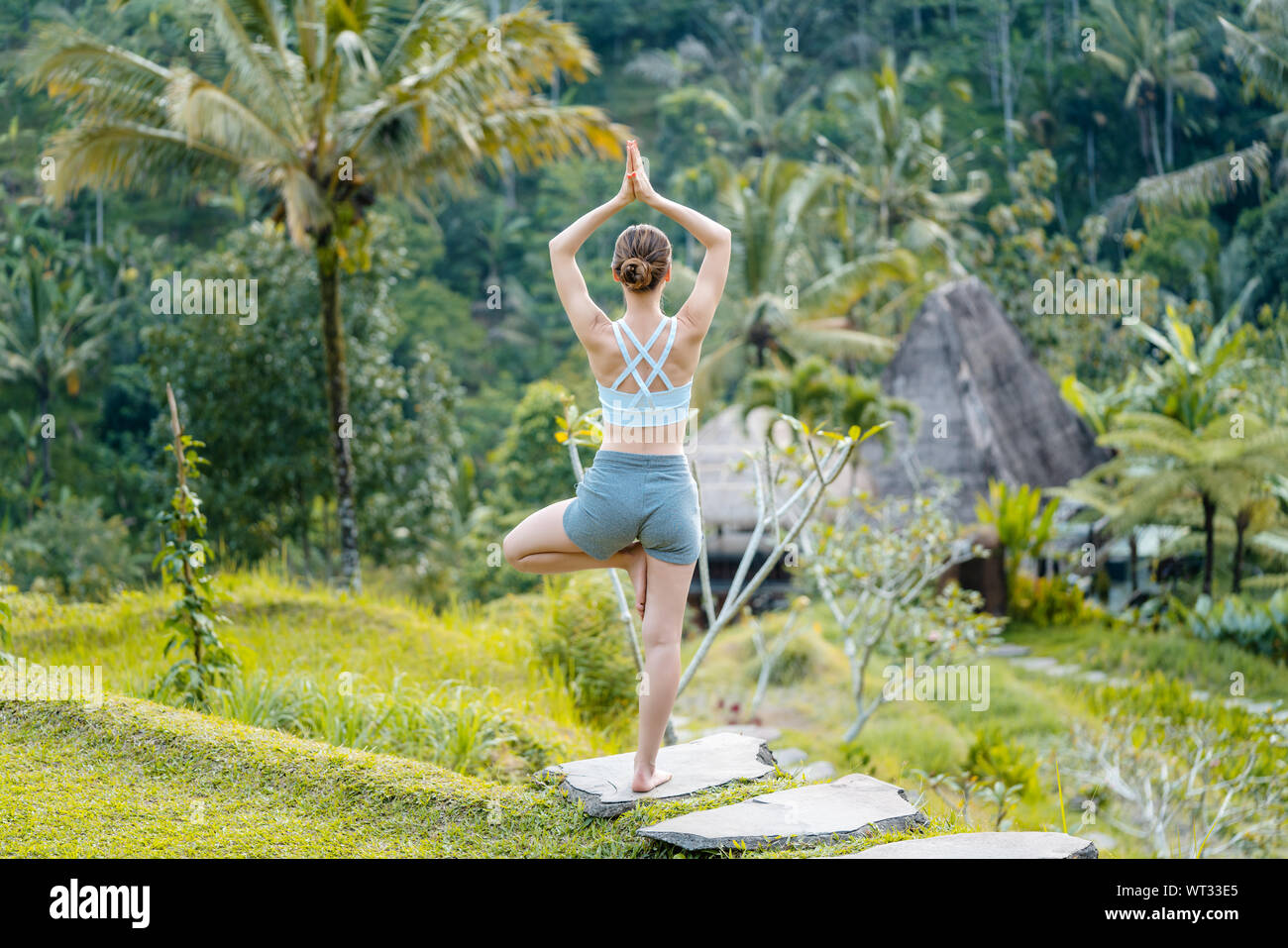 Woman on rice paddy in yoga pose Stock Photo - Alamy