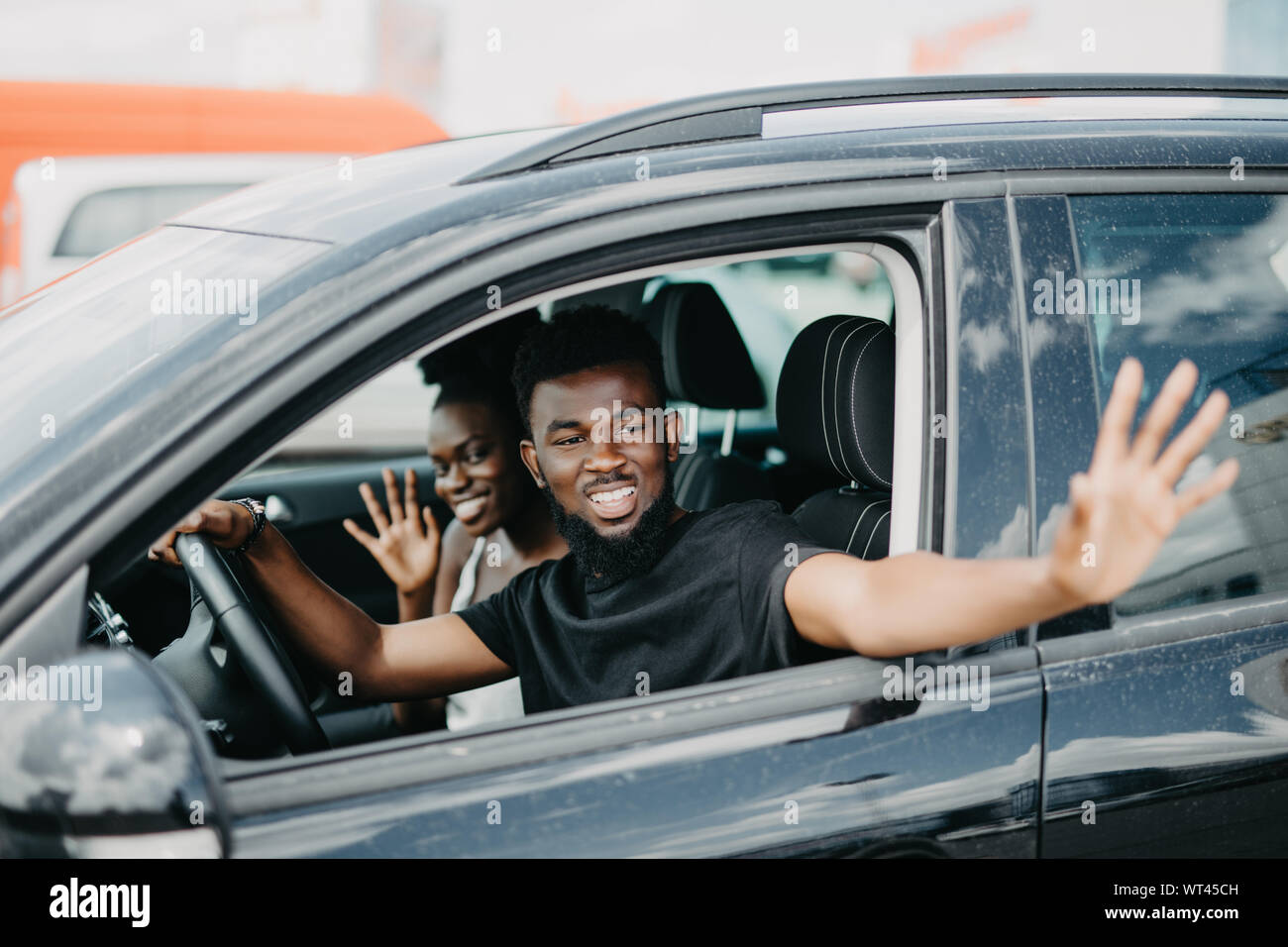 Young man greeting someone while drive car on the street Stock Photo ...