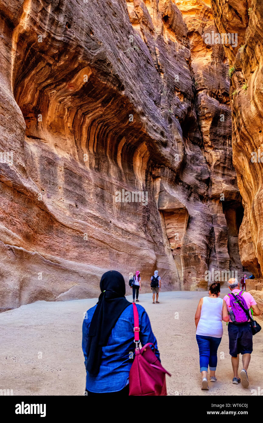 Tourists walking through the narrow gorge known as 'the Siq' leading to ...