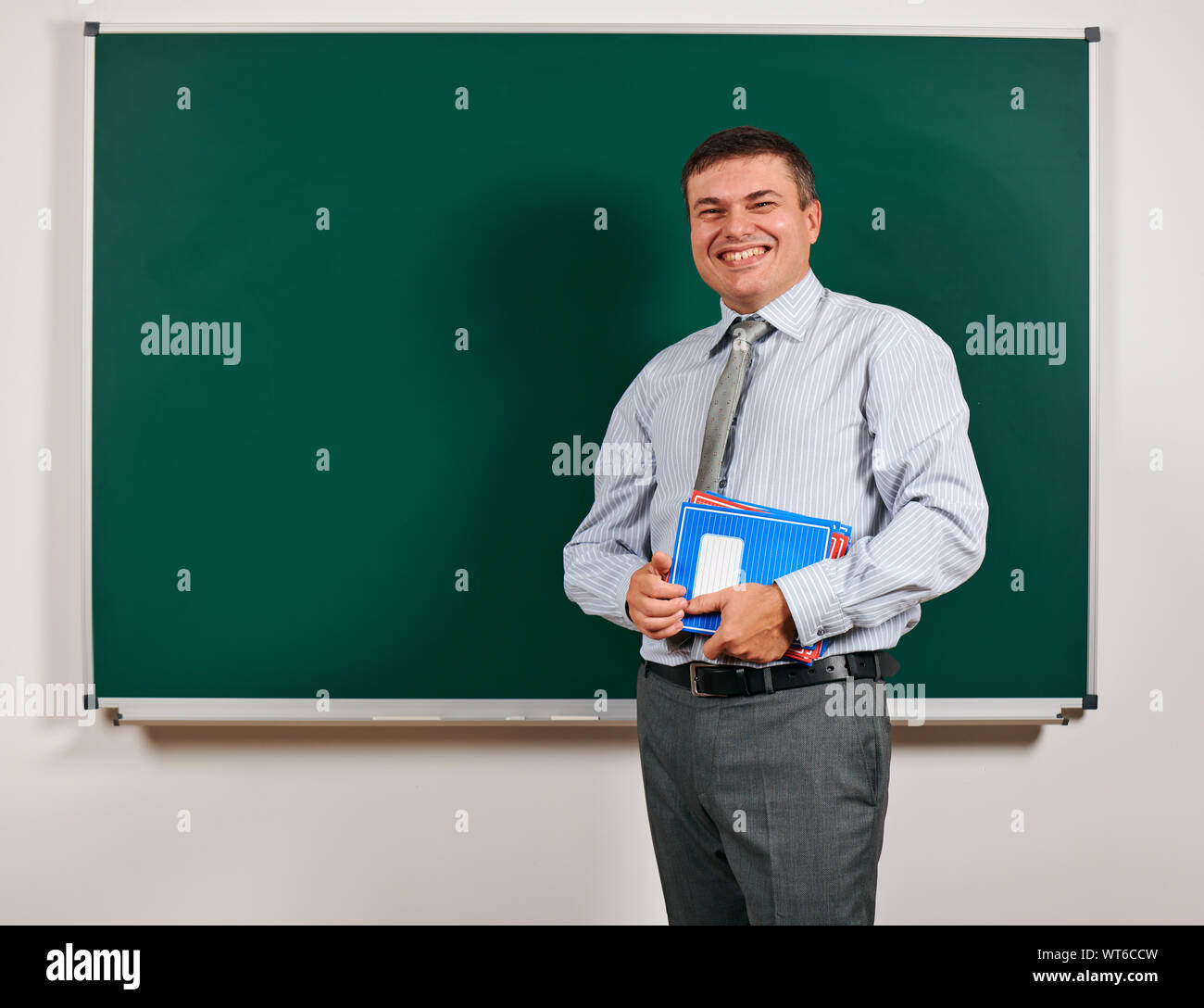 Portrait of a man as a teacher, posing at school board background ...