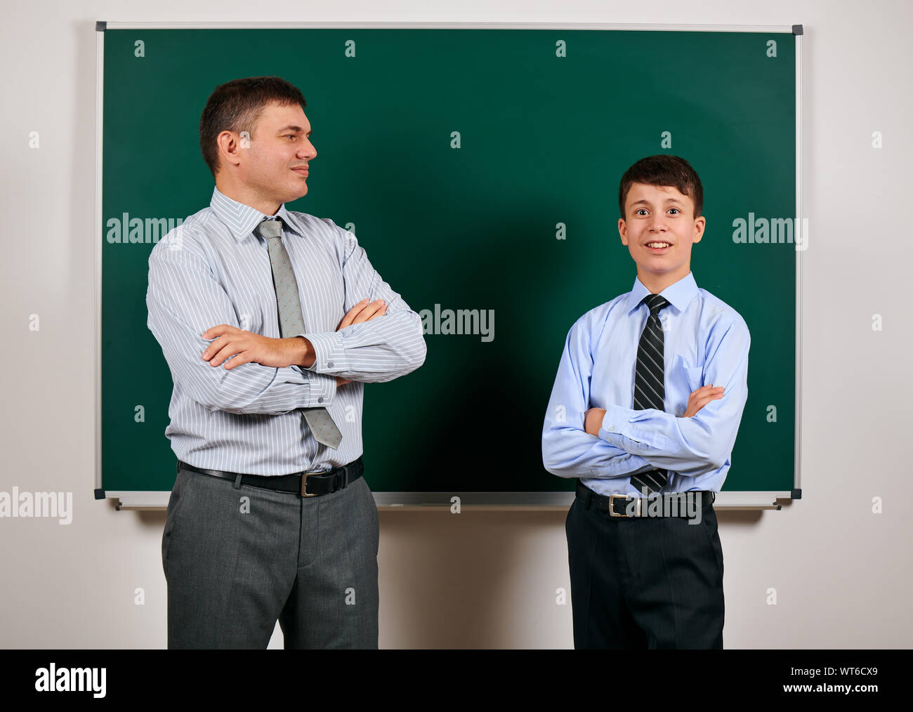 Portrait of a man and boy dressed in a business suits near blackboard ...