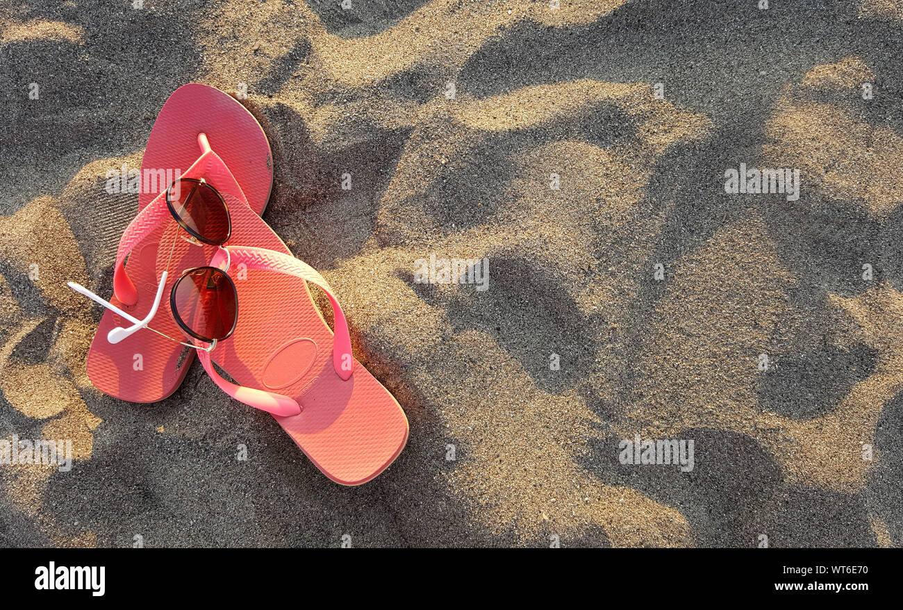 Beach slippers and sunglasses in the sand Stock Photo - Alamy
