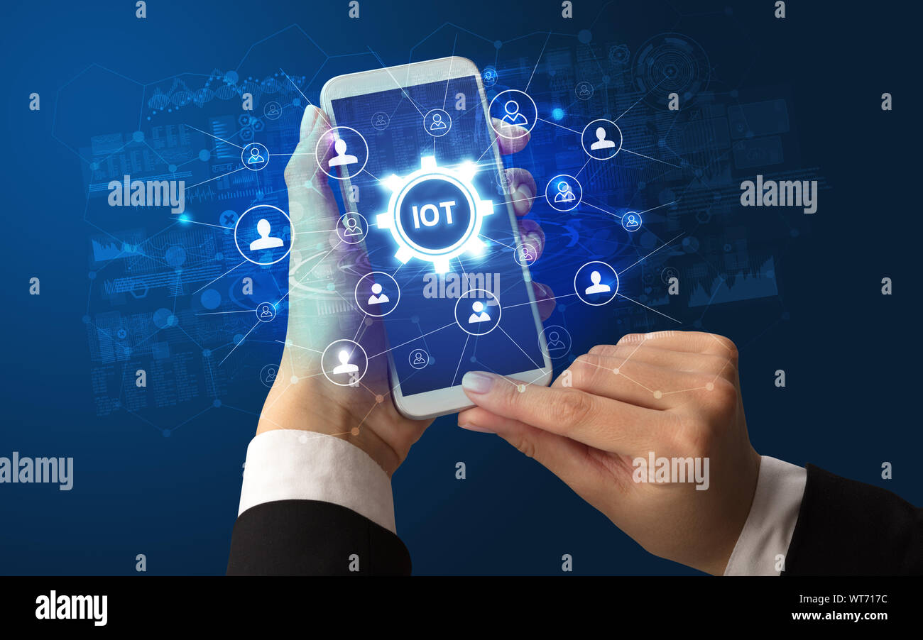 Female hand holding smartphone with IOT abbreviation, modern technology ...