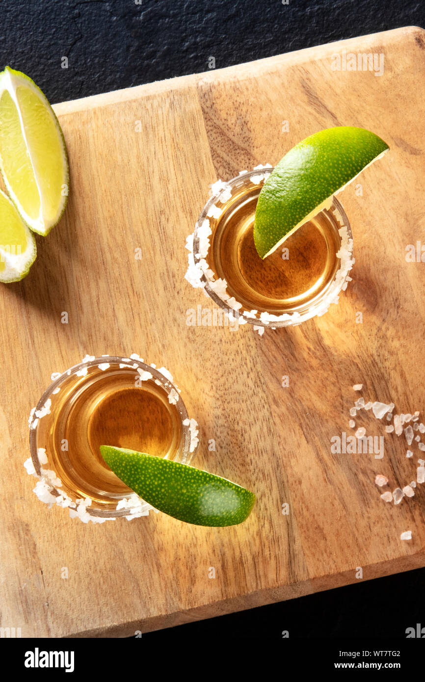 Golden tequila shots with salt rims and lime slices, overhead close-up ...
