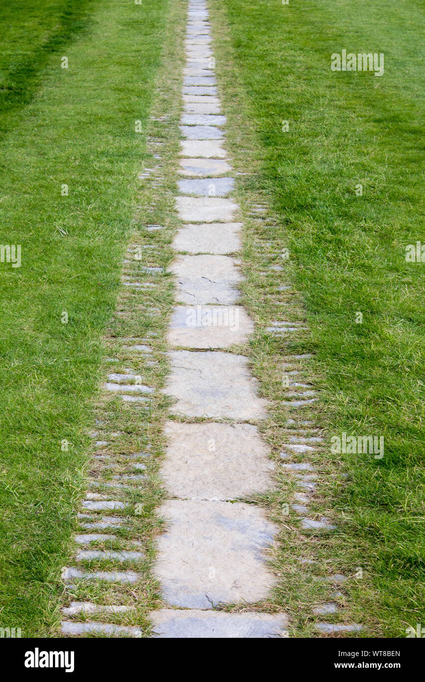 A garden path made from old stones, paving slabs on a grass lawn Stock ...